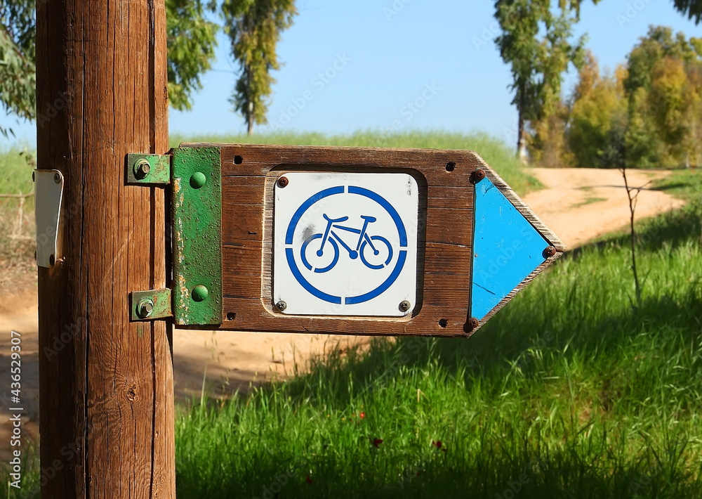 Wooden signpost with a bicycle symbol indicating the moving direction ...
