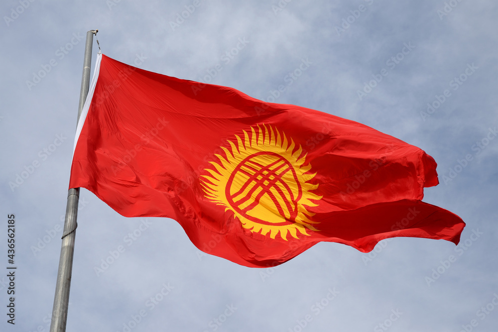 Kyrgyzstan flag waving at a pole in Bishkek. Red flag with yellow ...