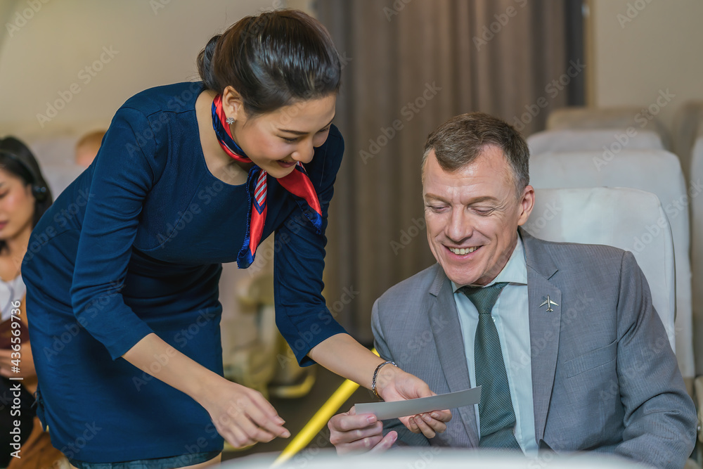 air hostess checking passengers boarding pass for seat in business ...