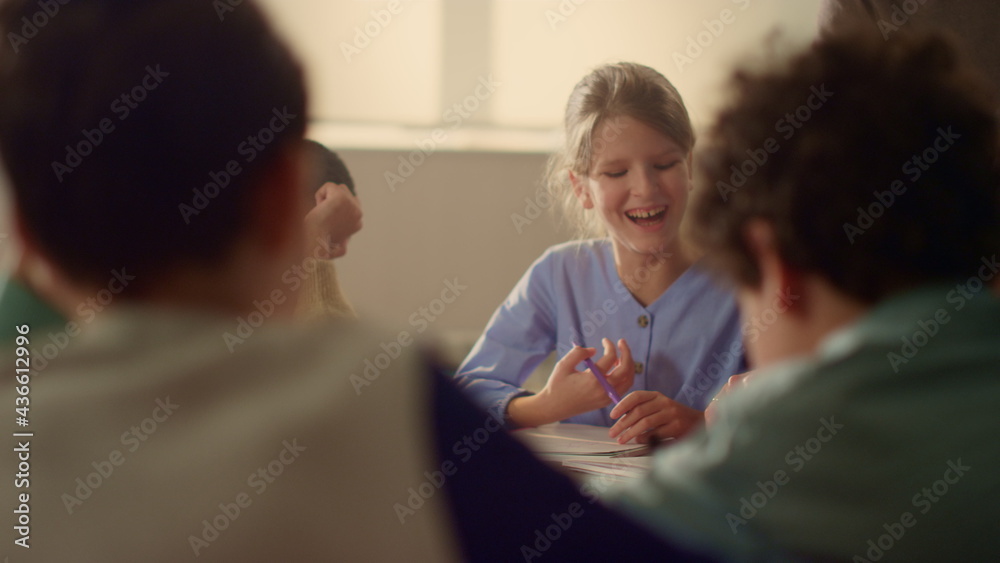 Children learning at round table in classroom. Pupils doing class work ...