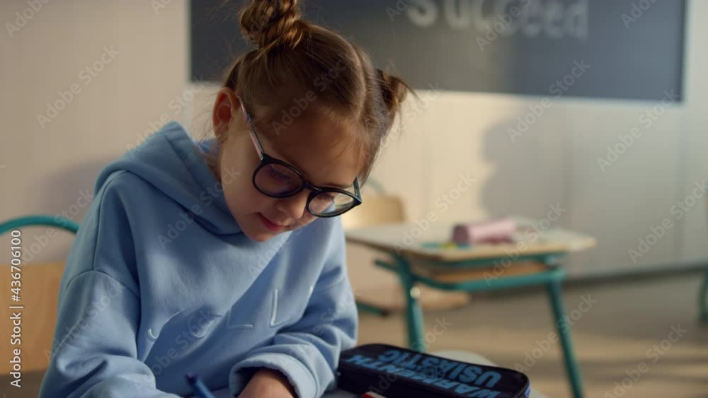 Focused child studying in class. Smart girl writing in notebook at ...