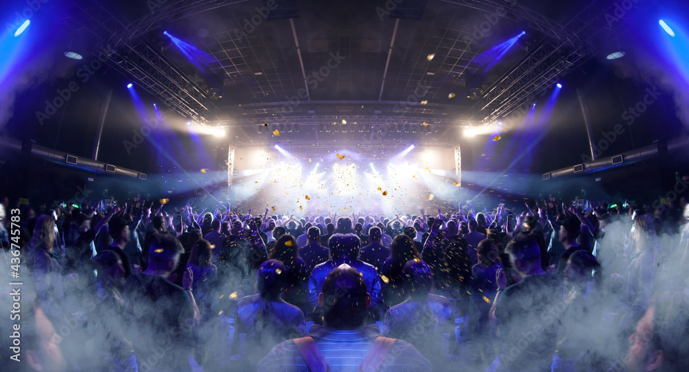 Concert crowd inside a venue, lens flare and smoke are visible. Stock ...