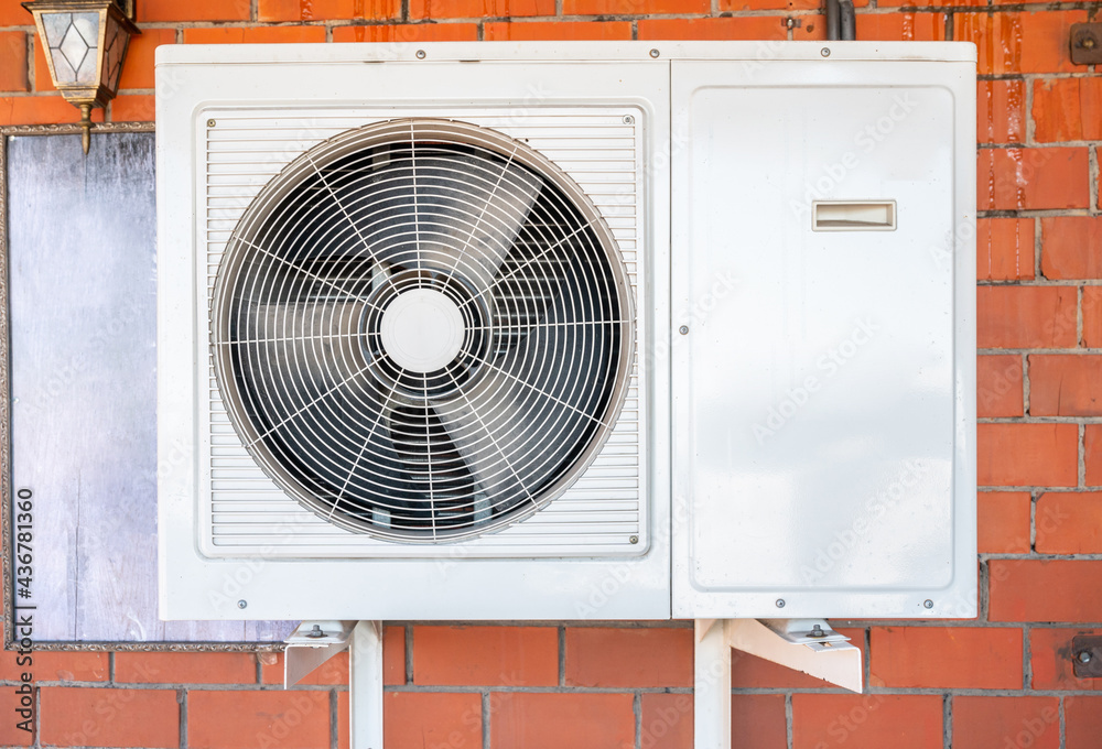 An air compressors setting on the building wall. An air compressor is a ...