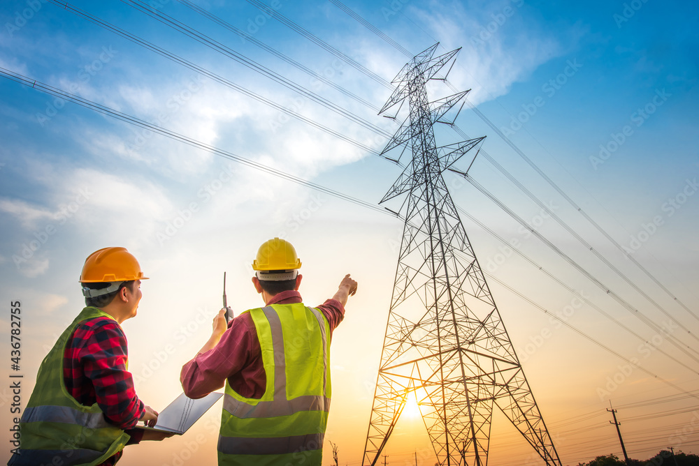 At the power plant, two electrical engineers are observing the high ...