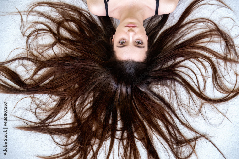 Beautiful young woman lying on the white background with long ...
