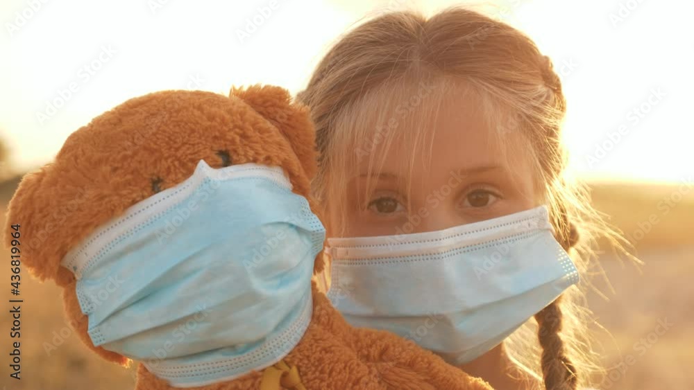 small cute child in protective mask on his face holds teddy bear in ...