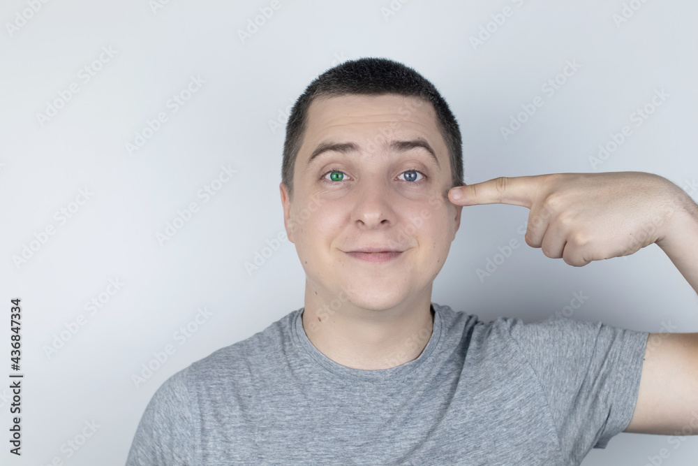 A man with different color eyes looks into the frame. The right eye is ...