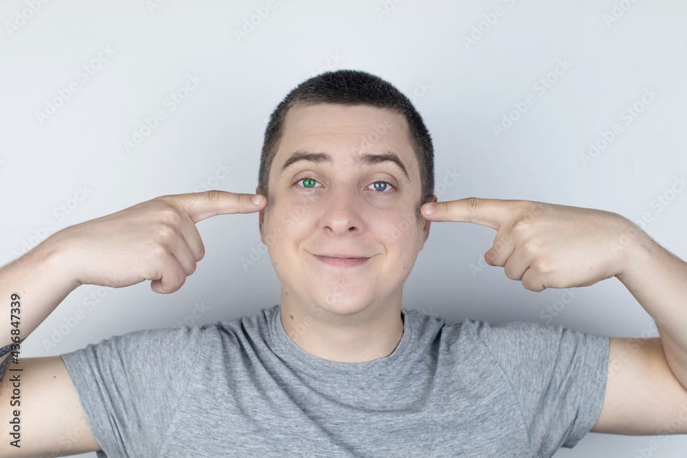 A man with different color eyes looks into the frame. The right eye is ...