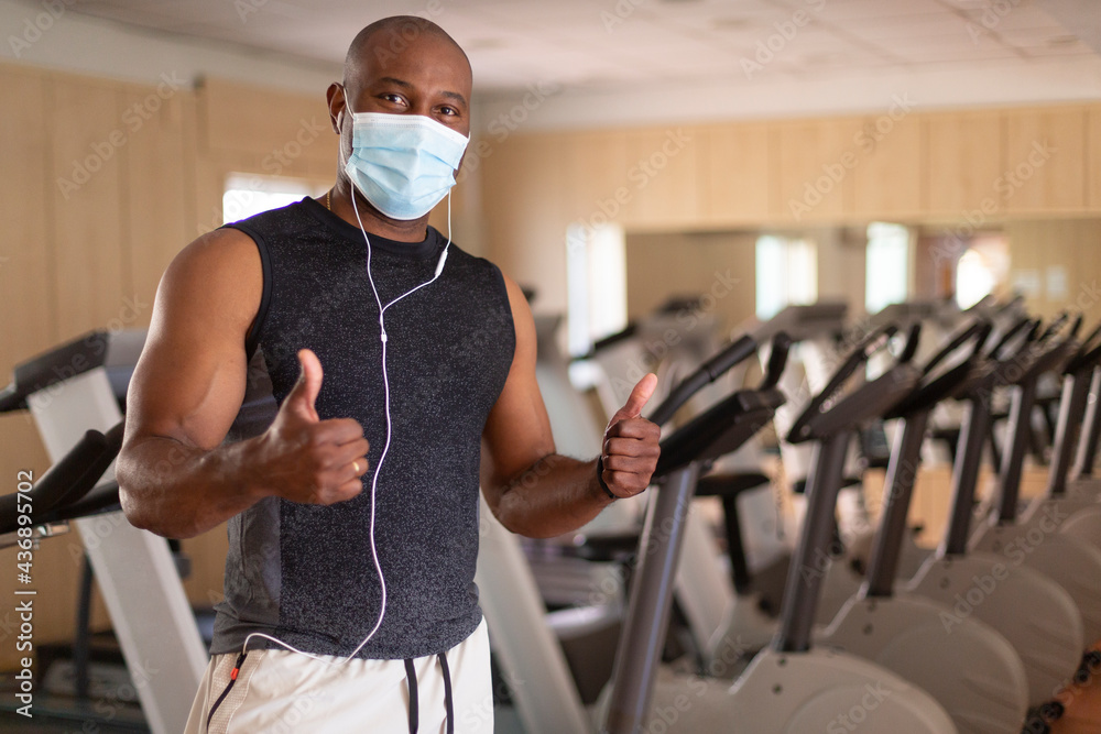 Portrait of black male sportsman with face mask. He is inside the gym ...