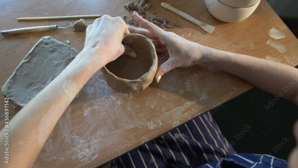 An unknown woman sculpts clay in pottery. Close-up of a woman's hands ...