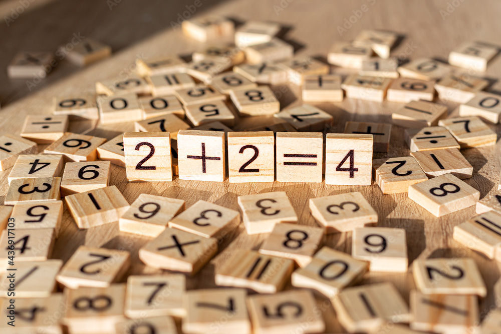 Scattered wooden plaques with numbers and signs. Two by two is four ...