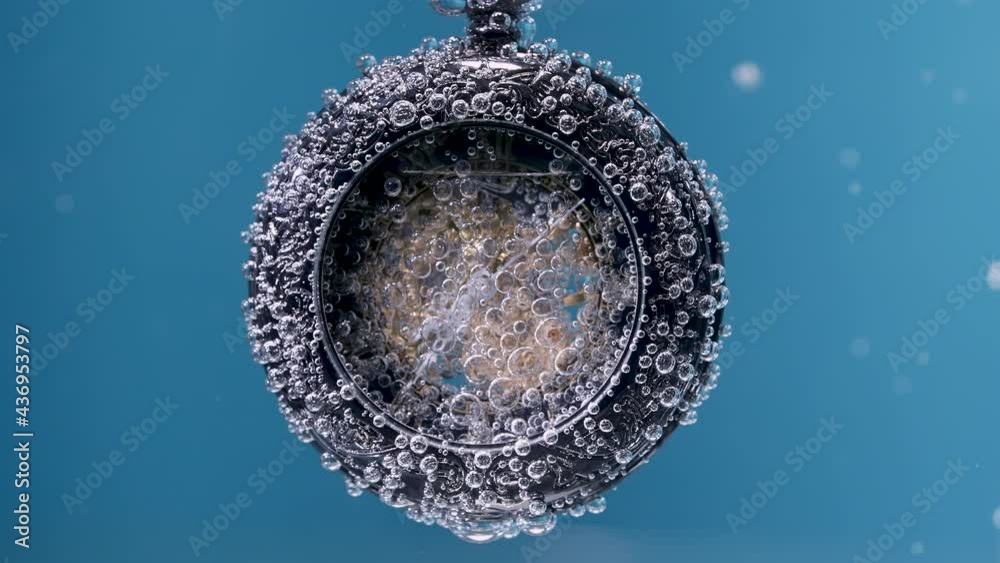 Vintage watch on a chain covered with air bubbles in transparent water ...