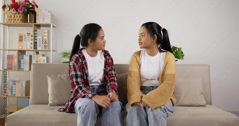 Sad young twin girls sit back to each other after a quarrel with her ...