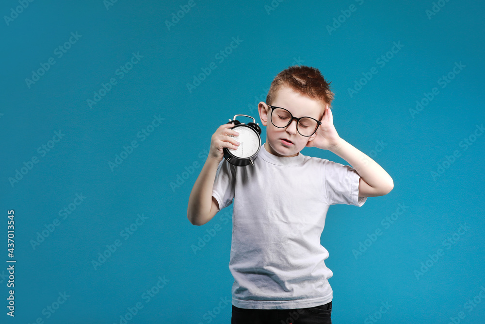 Little boy waking up with alarm clock, isolated on the blue background ...
