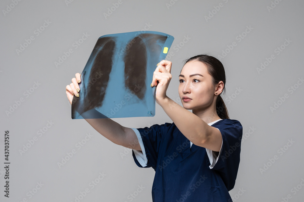 attractive young female asian doctor in white coat looking at X-Ray ...