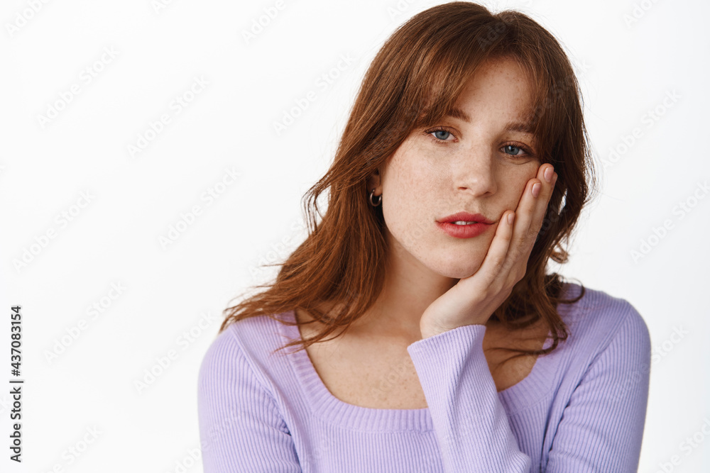 Close up of tired young girl with freckles and bangs, lean face on hand ...