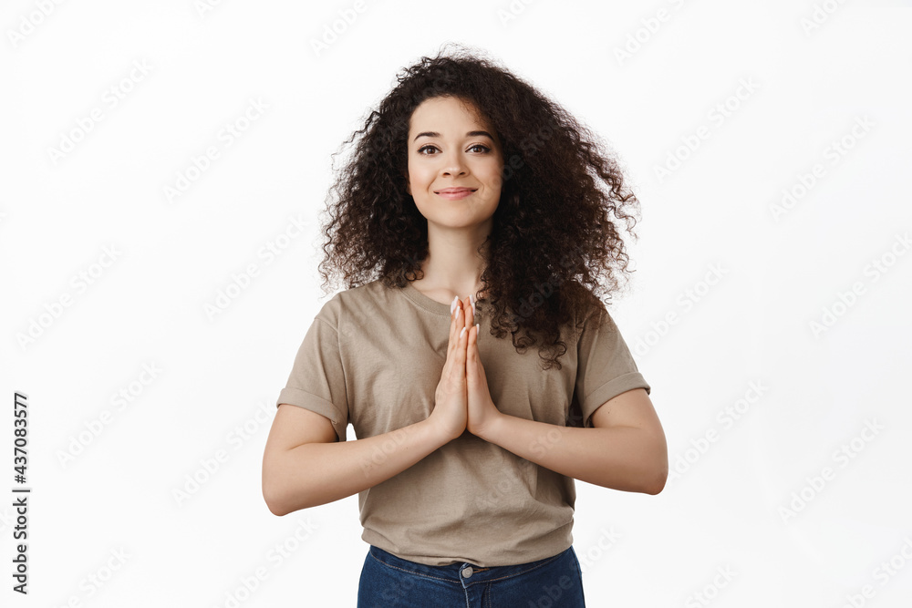 Namaste. Smiling relaxed brunette woman holding palms together, looking ...