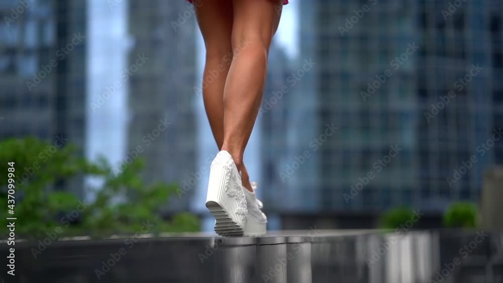 women's feet in white high-soled shoes walk along the parapet against ...
