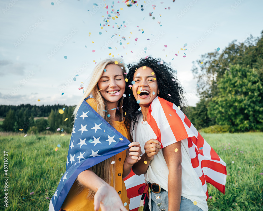 Two happy women covered by the USA flag. Young friends celebrating the ...