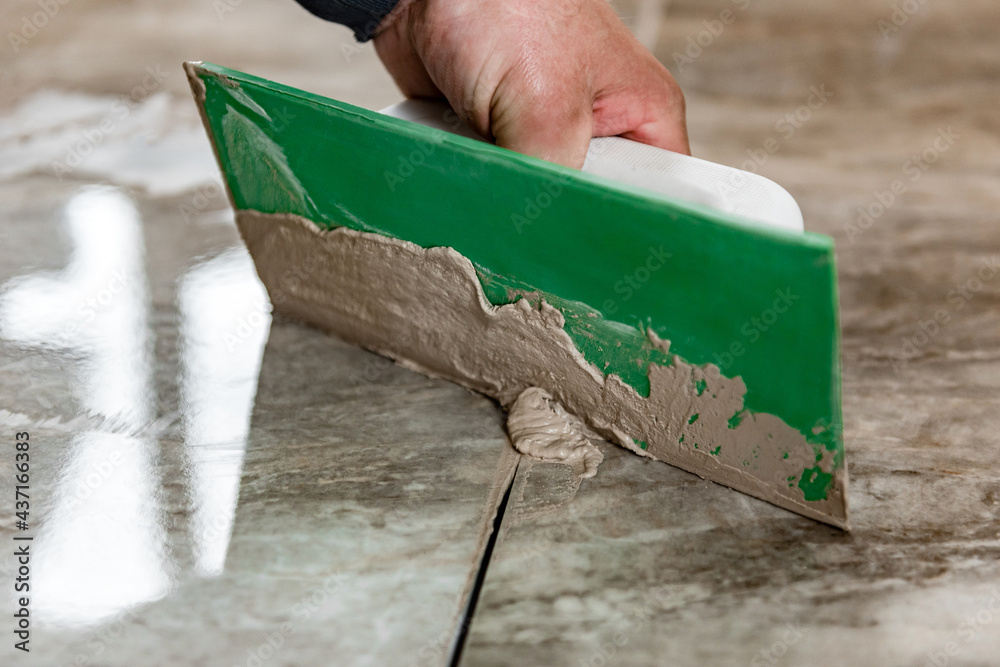 Grouting ceramic tiles. Tilers filling the space between tiles using a ...