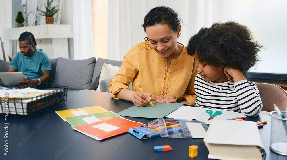 Family day. Mother helps her daughter do school homework while father ... Family day. Mother helps her daughter do school homework while father ...