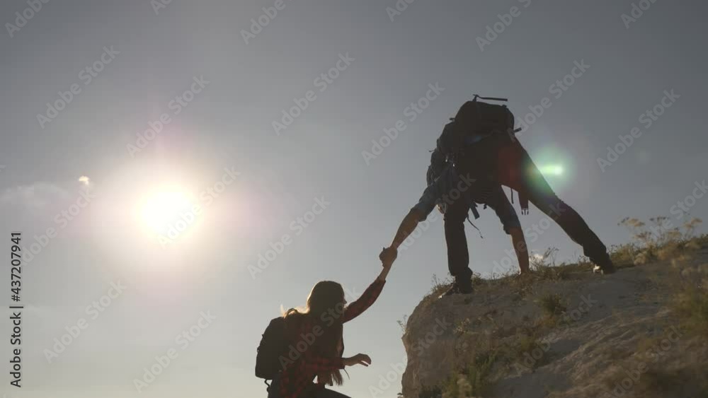 Teamwork. A couple of tourists lend a helping hand while climbing the ...