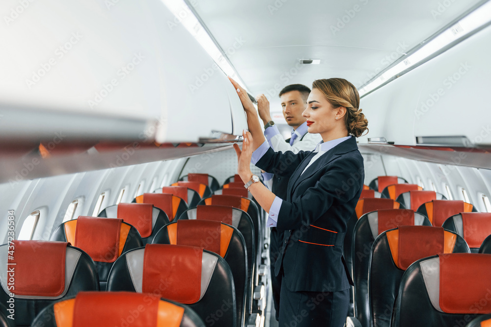 Young stewardess with steward on the work in the passanger airplane ...