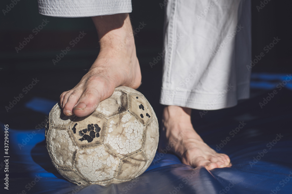 Karate football. A man in a white kimono stands with his foot on a ...