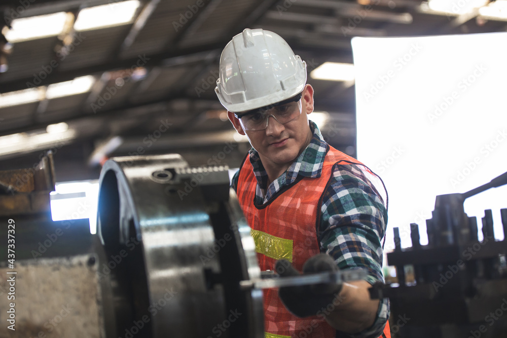 Foto de worker is working on a lathe machine in a factory. Turner ...