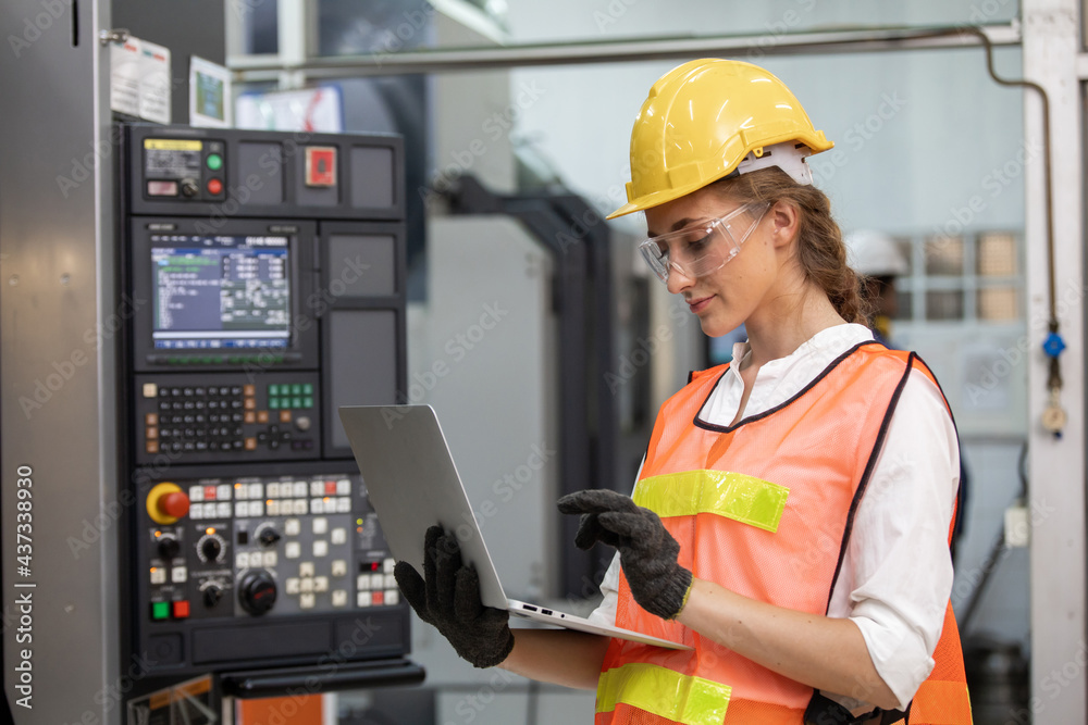 Factory worker is programming a CNC milling machine with a tablet ...
