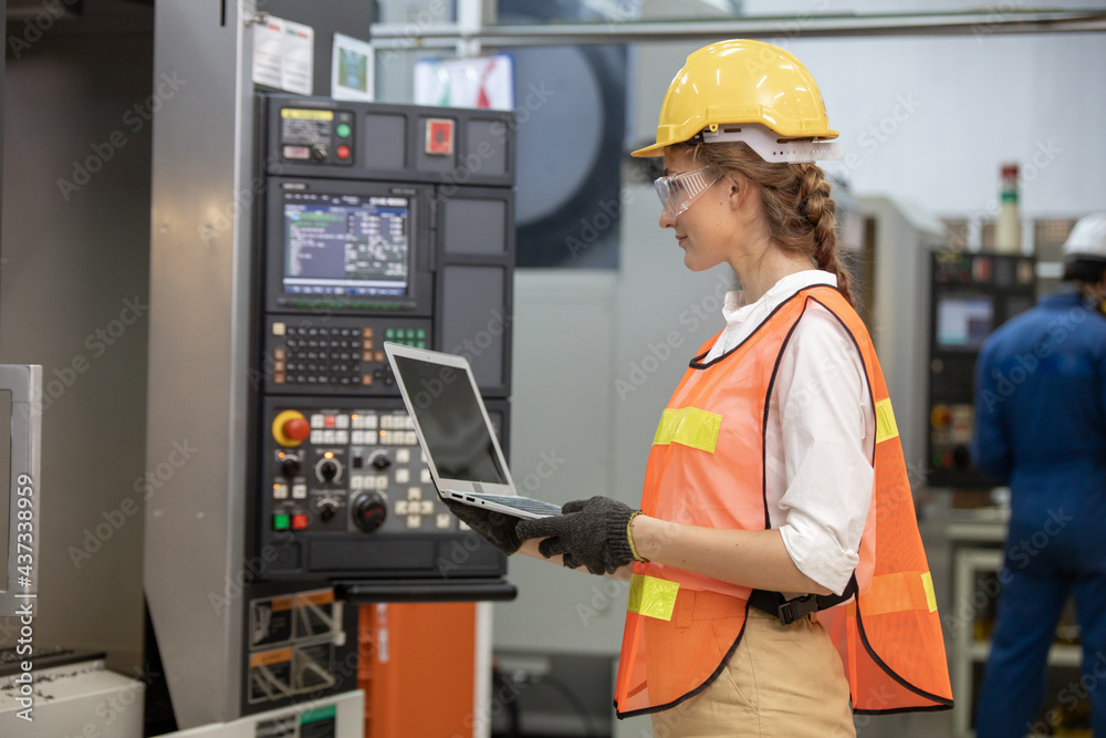 Factory worker is programming a CNC milling machine with a tablet ...
