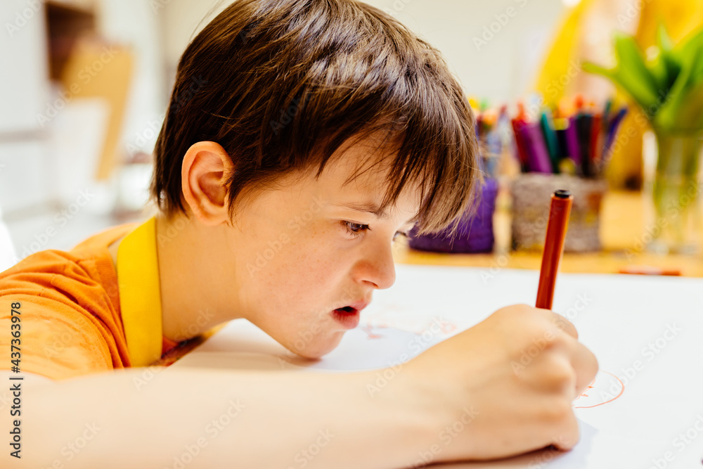 Side view of handsome little boy down syndrome learning about drawing ...