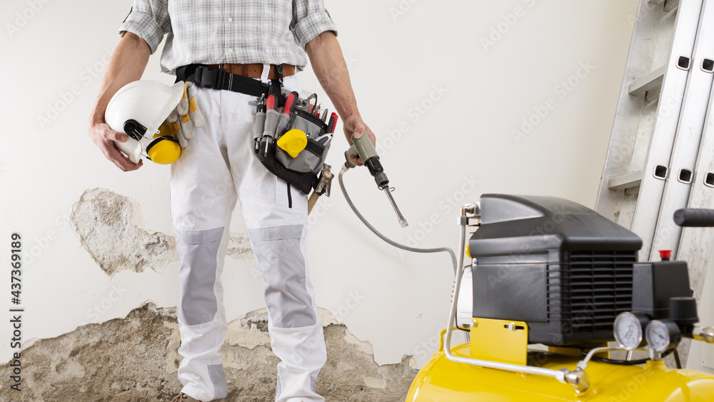construction man worker wearing a tool bag belt, helmet with headphones ...