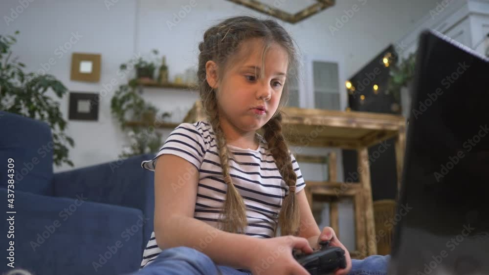 Happy girl playing video games with a joystick. Child gambling ...