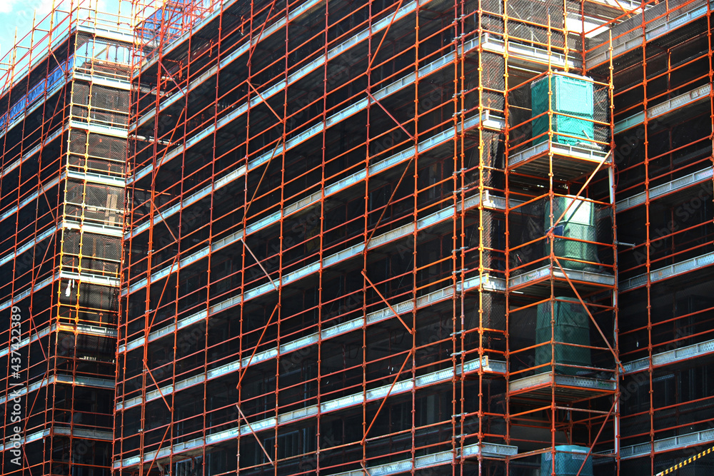 Multi storey apartment block construction site. Orange scaffolding ...