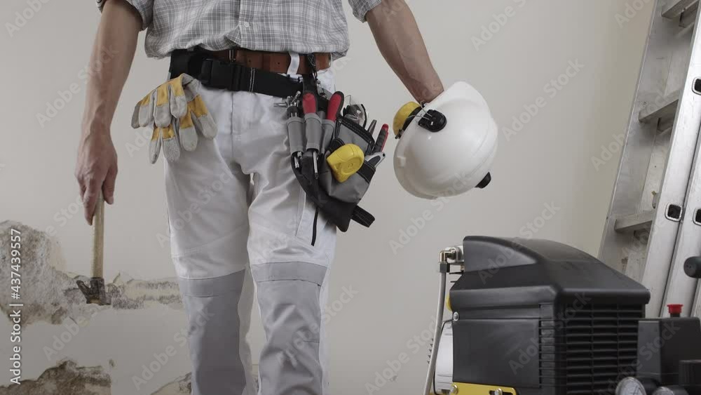 construction man worker wearing a tool bag belt, helmet with headphones ...