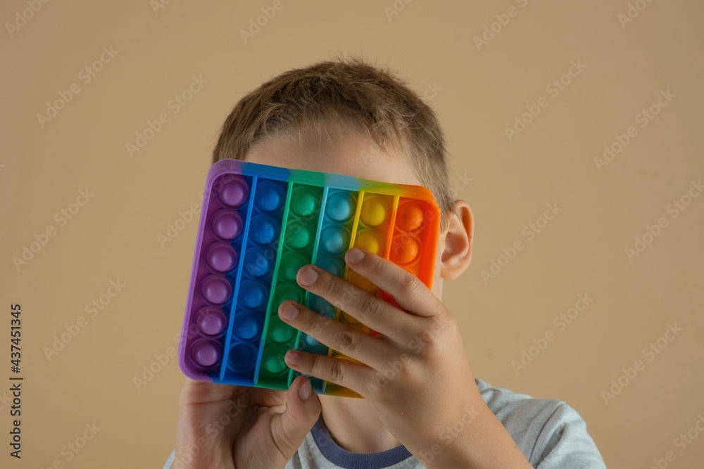 Portrait little boy with a modern popit toy. Colorful and bright pop it ...