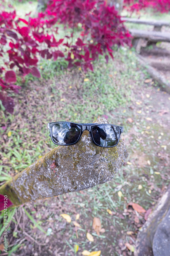 Black clip-on eyeglass frame on a rock in the photo from the front with ...