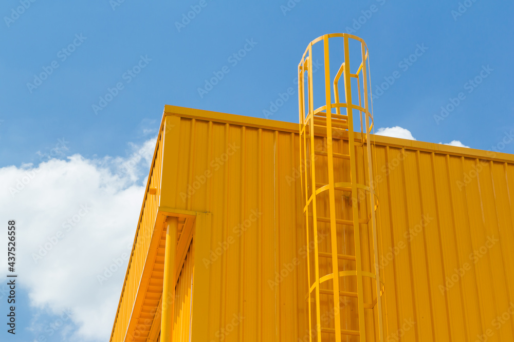 yellow steel staircase of factory against blue sky. service steel stair ...