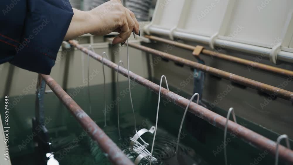 Processing of the part in a galvanic chemical bath. A female worker ...