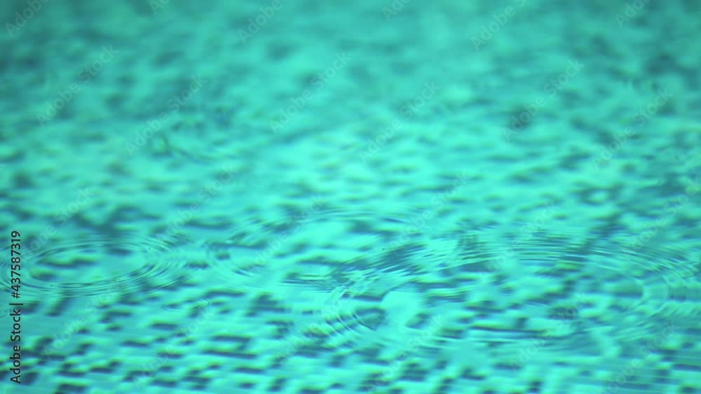 Rain drops falling on the surface of the swimming pool with that ripple ...