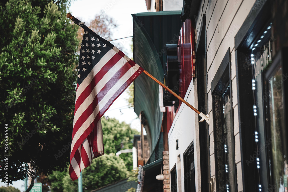 American flag hanging on building in downtown area of city Stock Photo ...