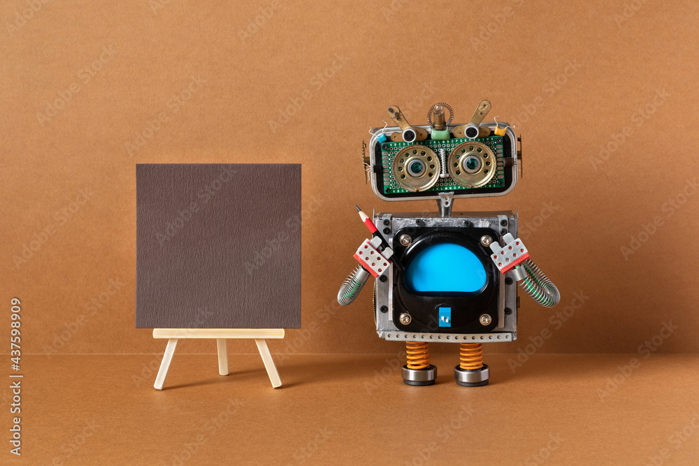 A robot artist poses with a pencil next to a wooden easel and a blank ...