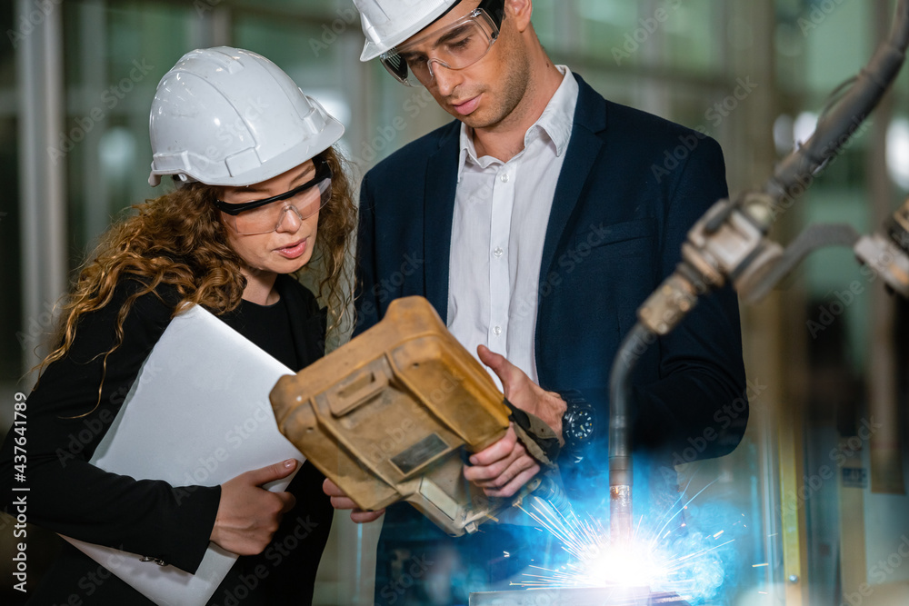 man engineer and female assistant wearing black suit and white hard hat ...