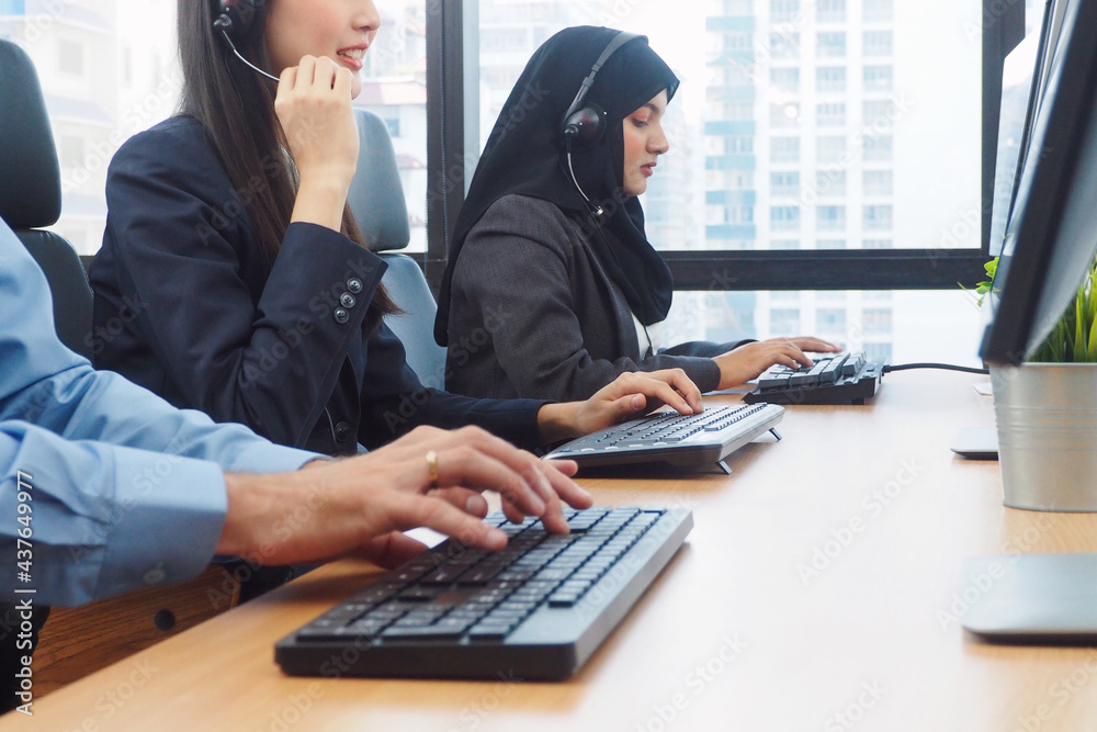 Call center with their headsets and microphone typing on keyboards ...