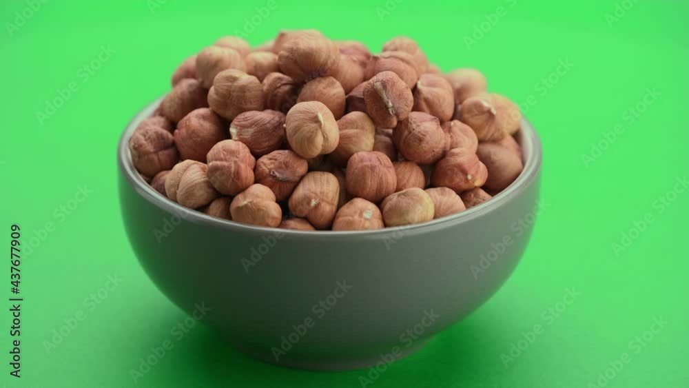 Hazelnut in a bowl rotate on their axis, isolated on a green screen ...