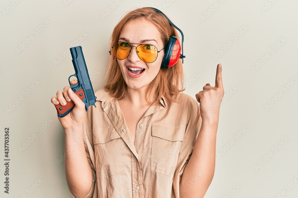 Young caucasian shooter woman using gun smiling with an idea or ...