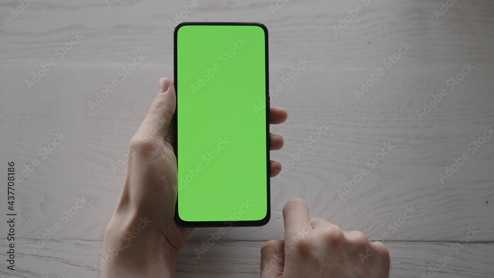 Man using phone with green screen on white oak table Stock Photo ...