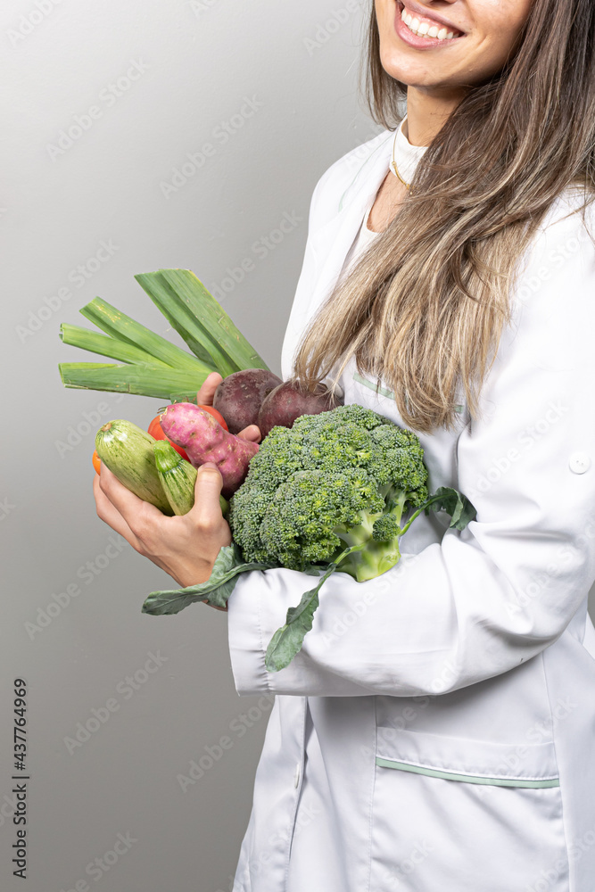 Smiling female nutritionist in her office, showing healthy vegetables ...