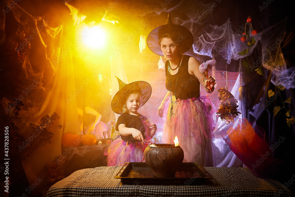 Beautiful brunette mother and cute little daughter looking as witches ...